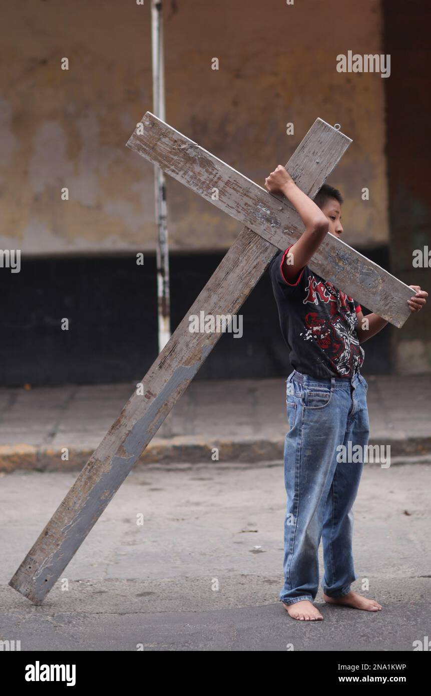 A boy carries a cross as he takes part in a procession during Holy Week ...