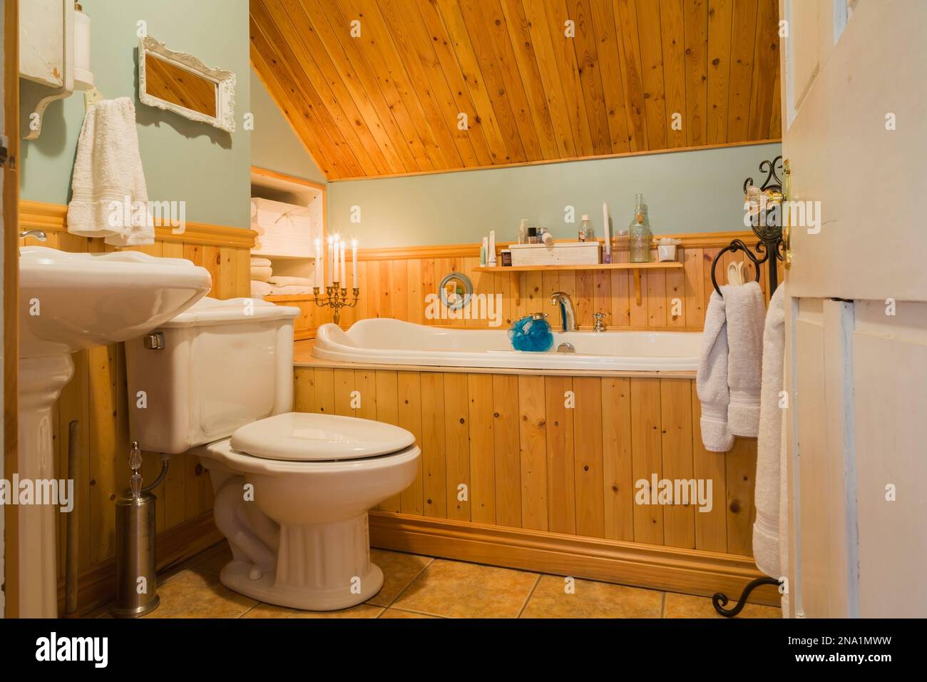 White therapeutic bathtub encased in a pinewood vertical plank base hi ...