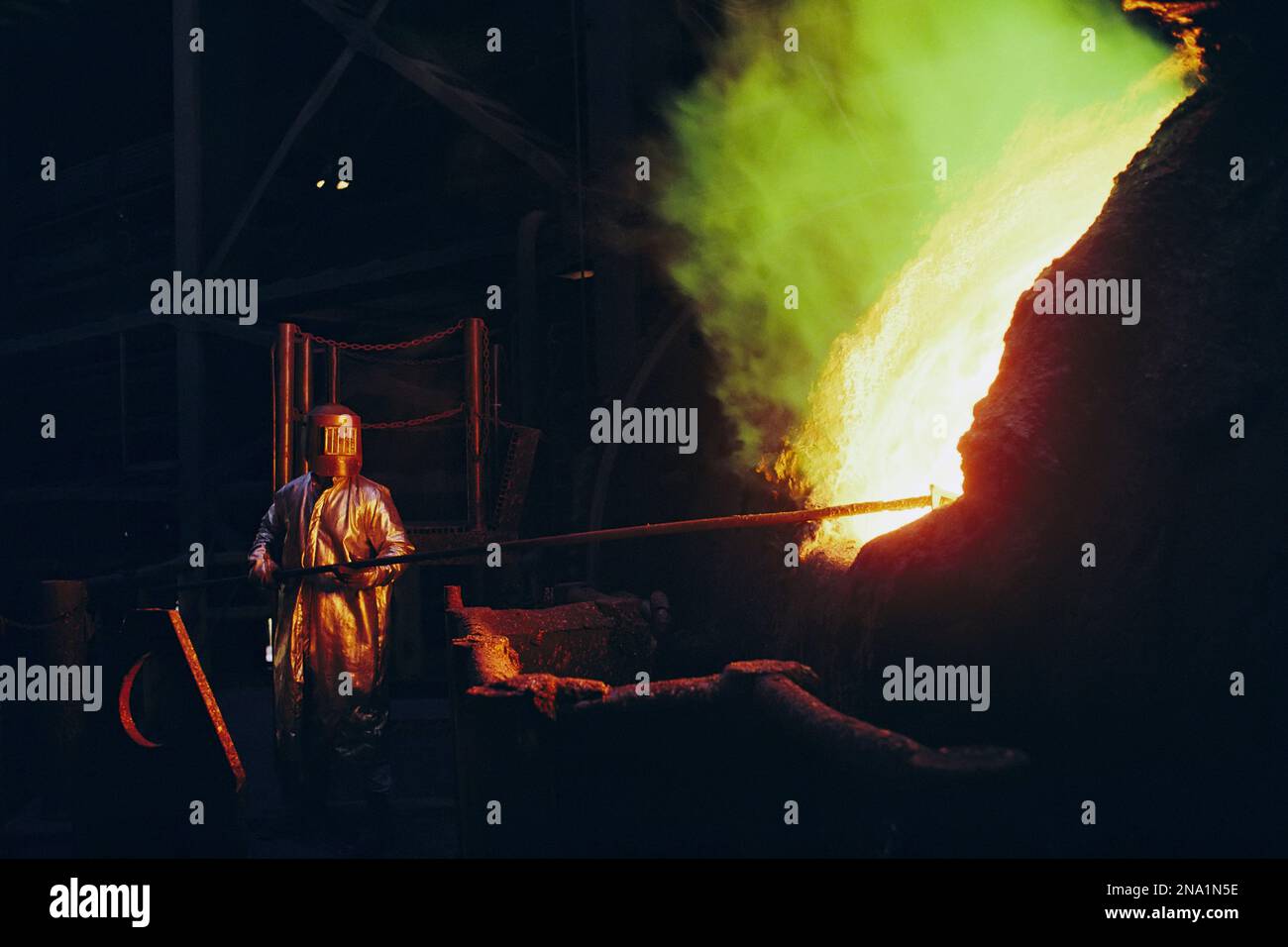 Man in protective gear tends a smelter at Magma Metals Company, near ...