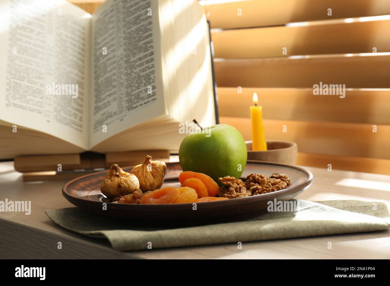 Dried fruits, apple, Bible and candle on window sill indoors. Great ...