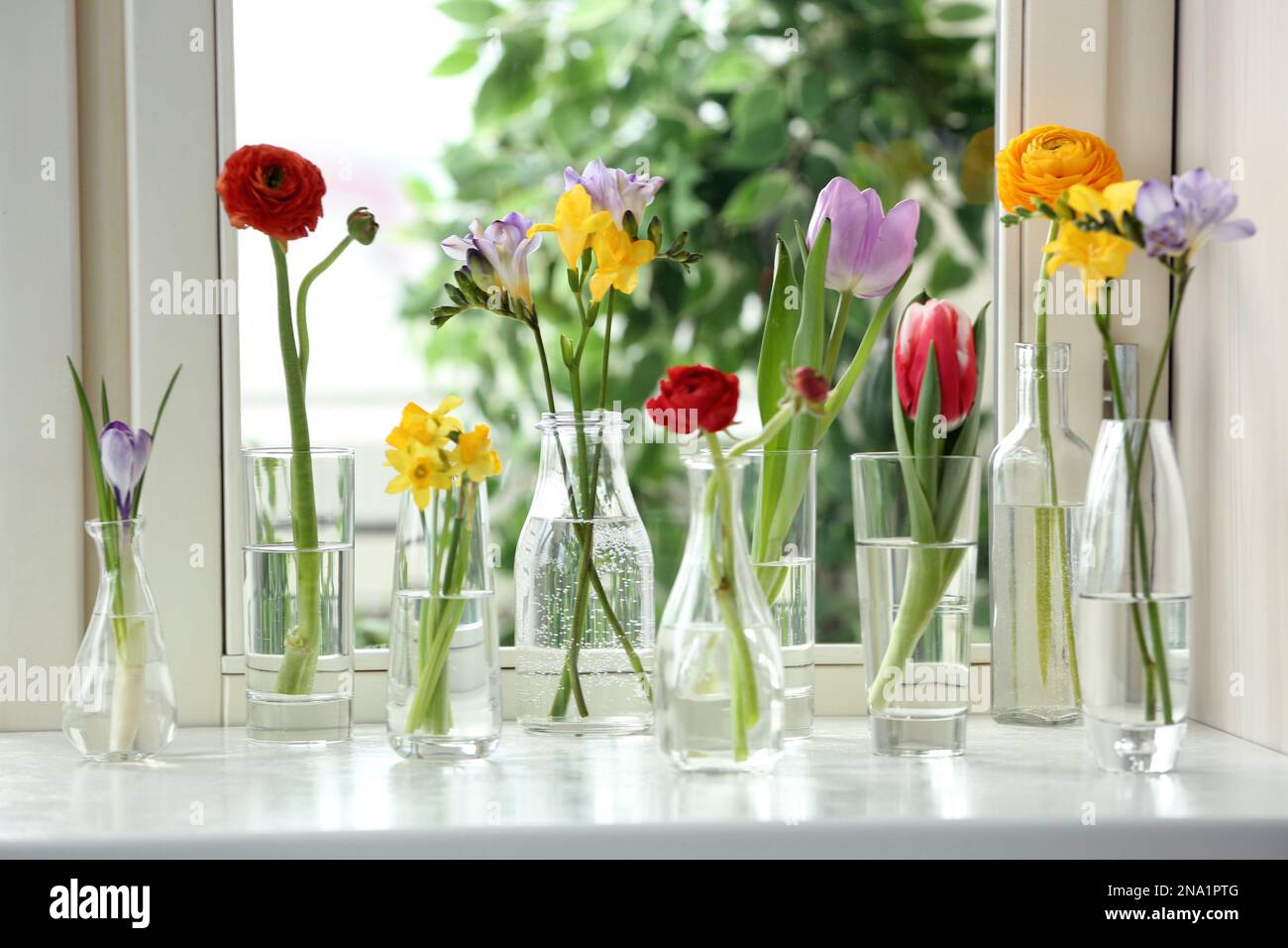 Beautiful spring flowers in glassware on window sill Stock Photo - Alamy