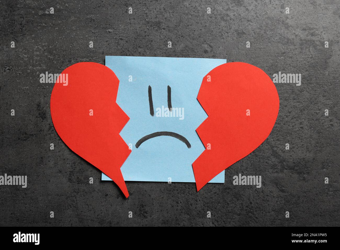Sticker with sad face and broken heart on grey background, flat lay ...