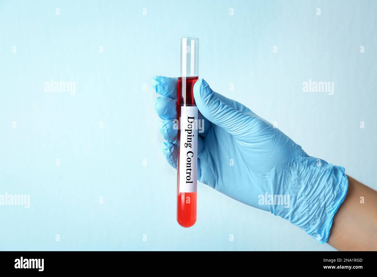 Woman holding test tube with sample on light background, closeup ...