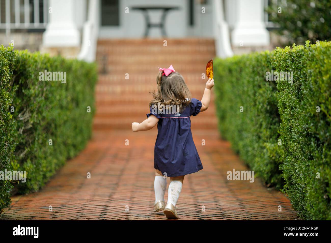A little girl running down a brick walkway path Stock Photo - Alamy