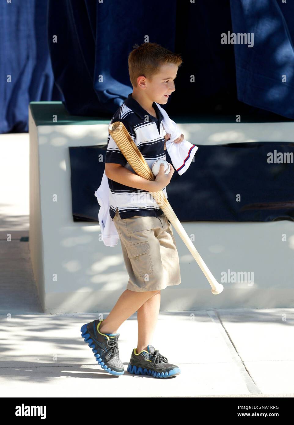Cooper Stone walks past an unveiled statue with a jersey, bat and ball ...