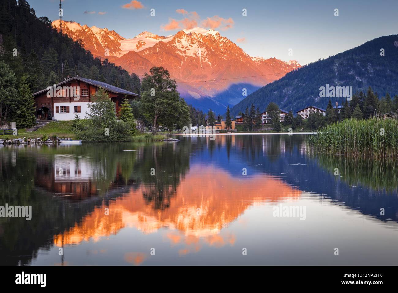 Pastel-coloured sunset glow on the mountains reflecting on Champex Lake ...