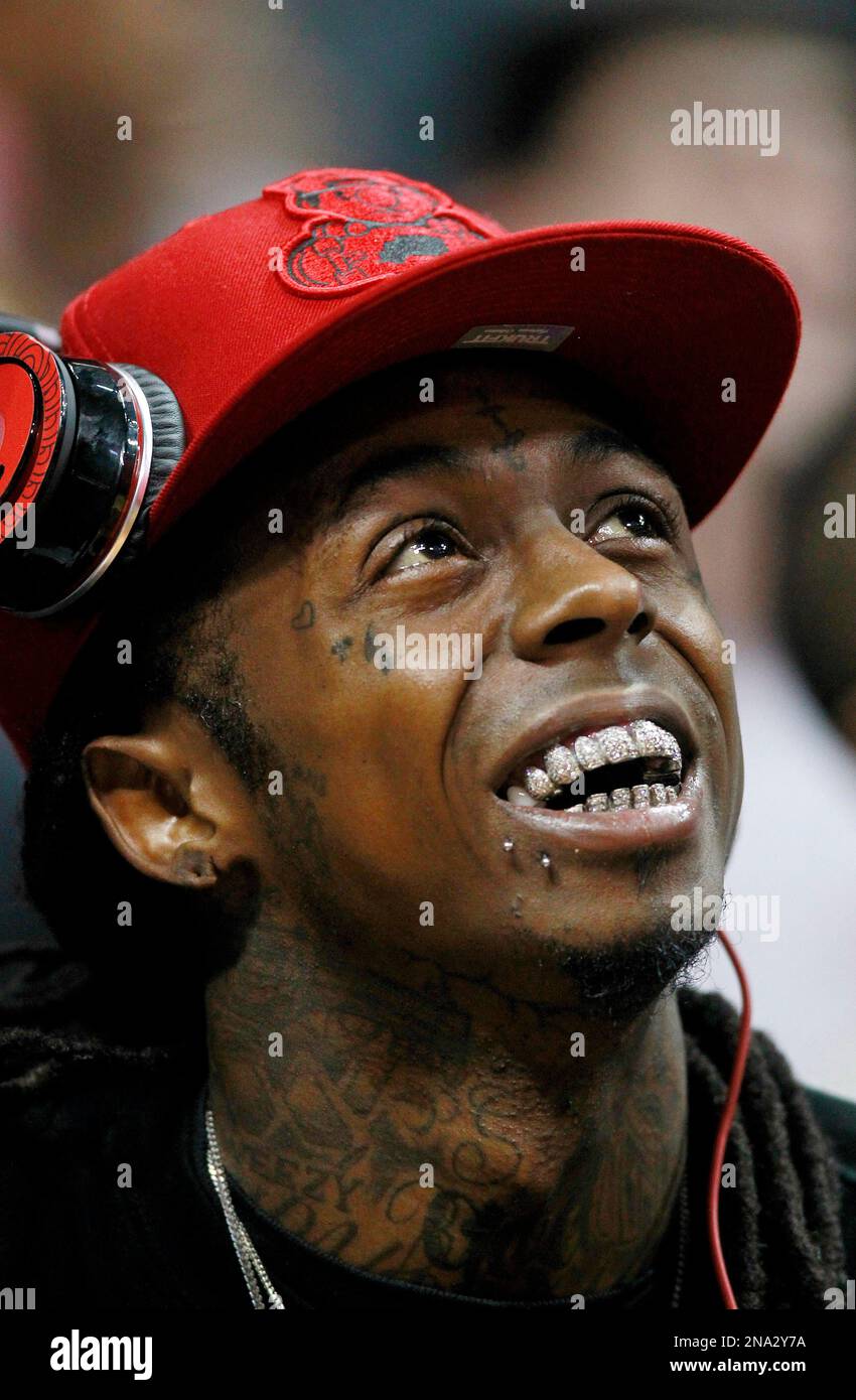 Rapper Lil Wayne sits courtside during an NBA basketball game between ...