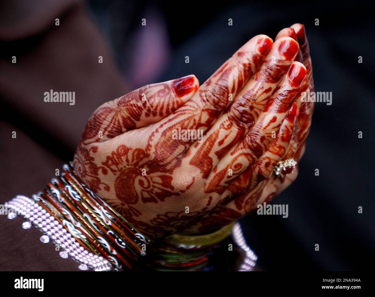 A Pakistani girl with her hands painted with henna, prays at a shrine ...