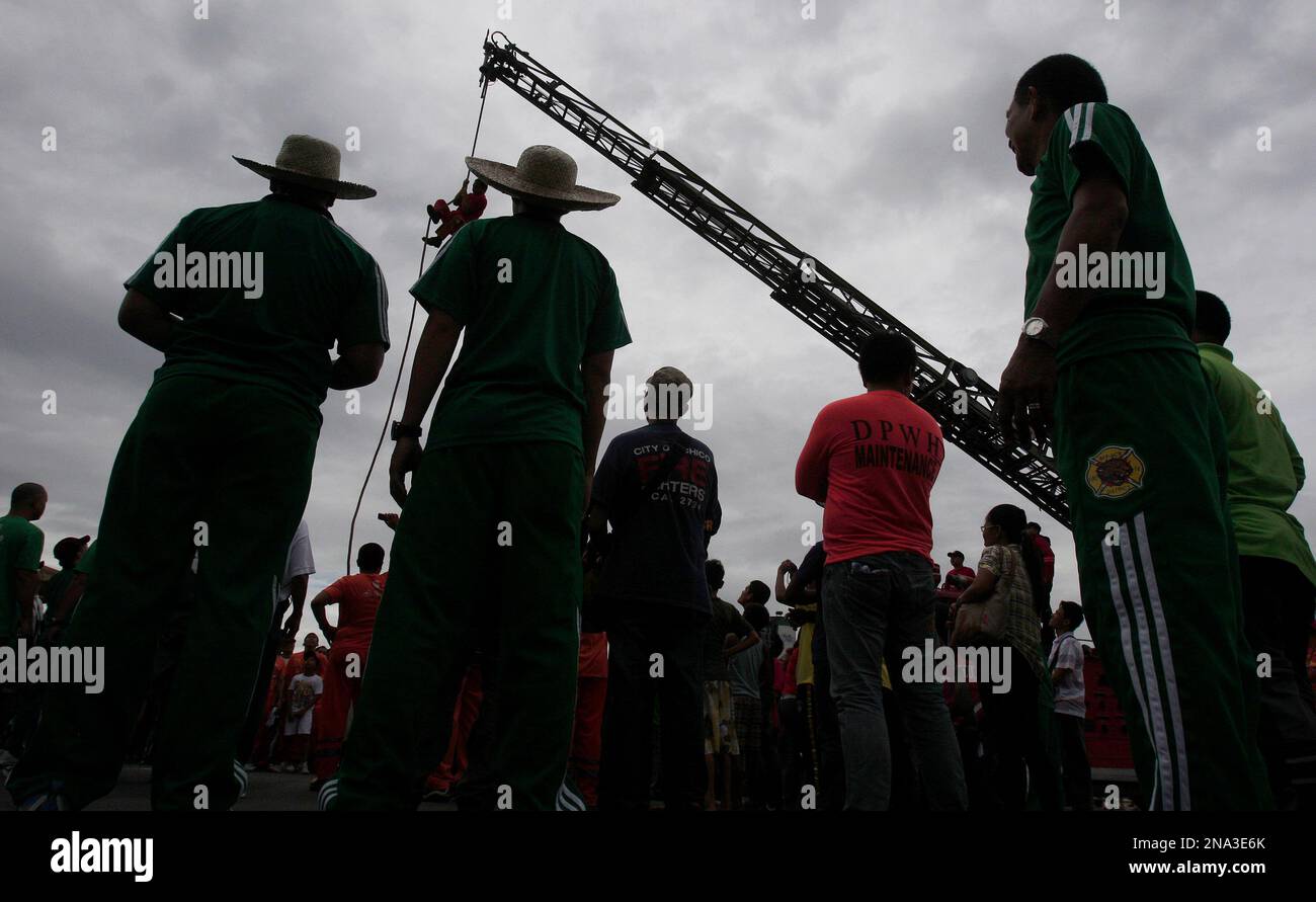 A crowd watches as a Filipino fireman participates in a rope climbing ...