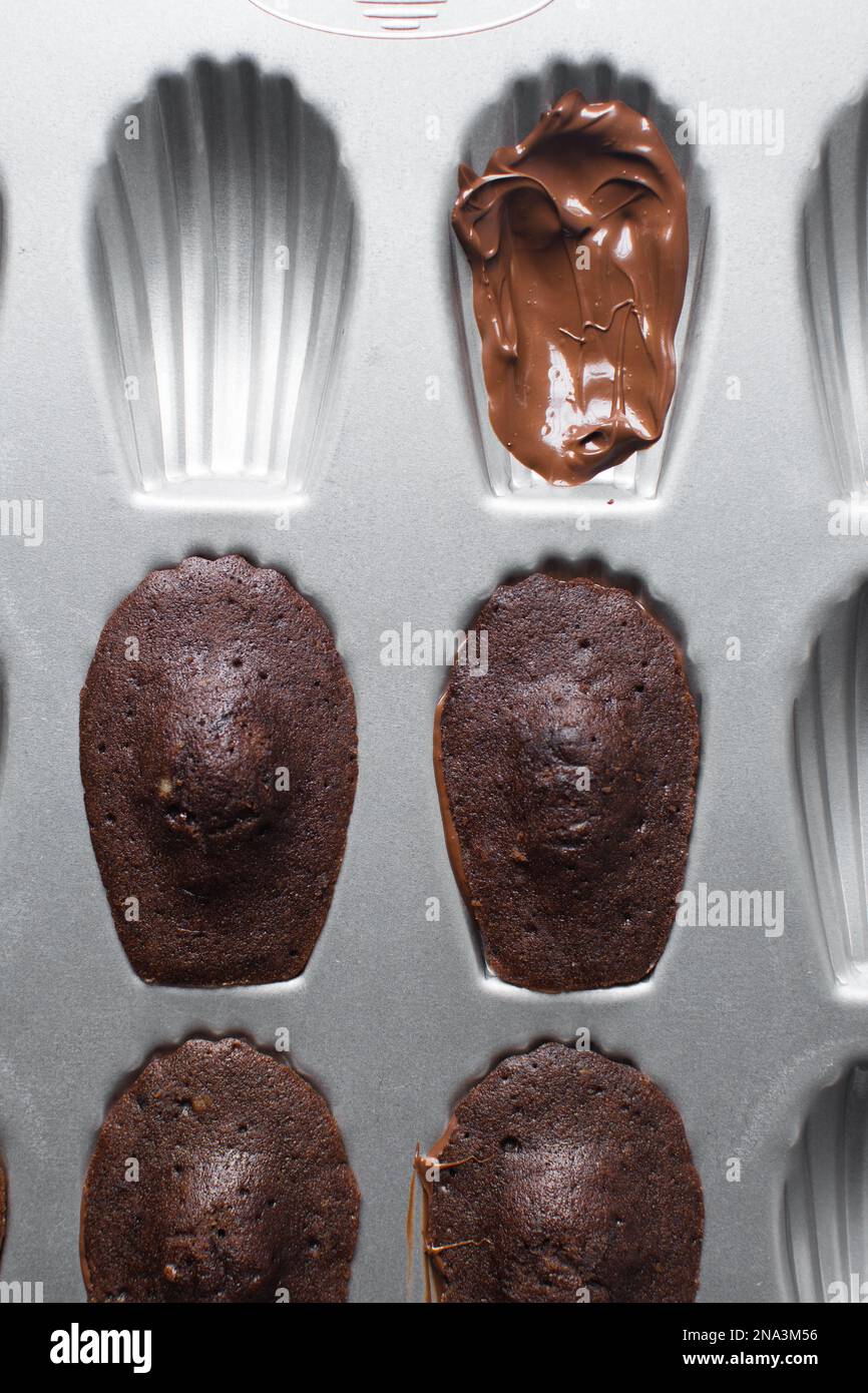 Melted chocolate in a madeleine pan, process of making chocolate coated ...