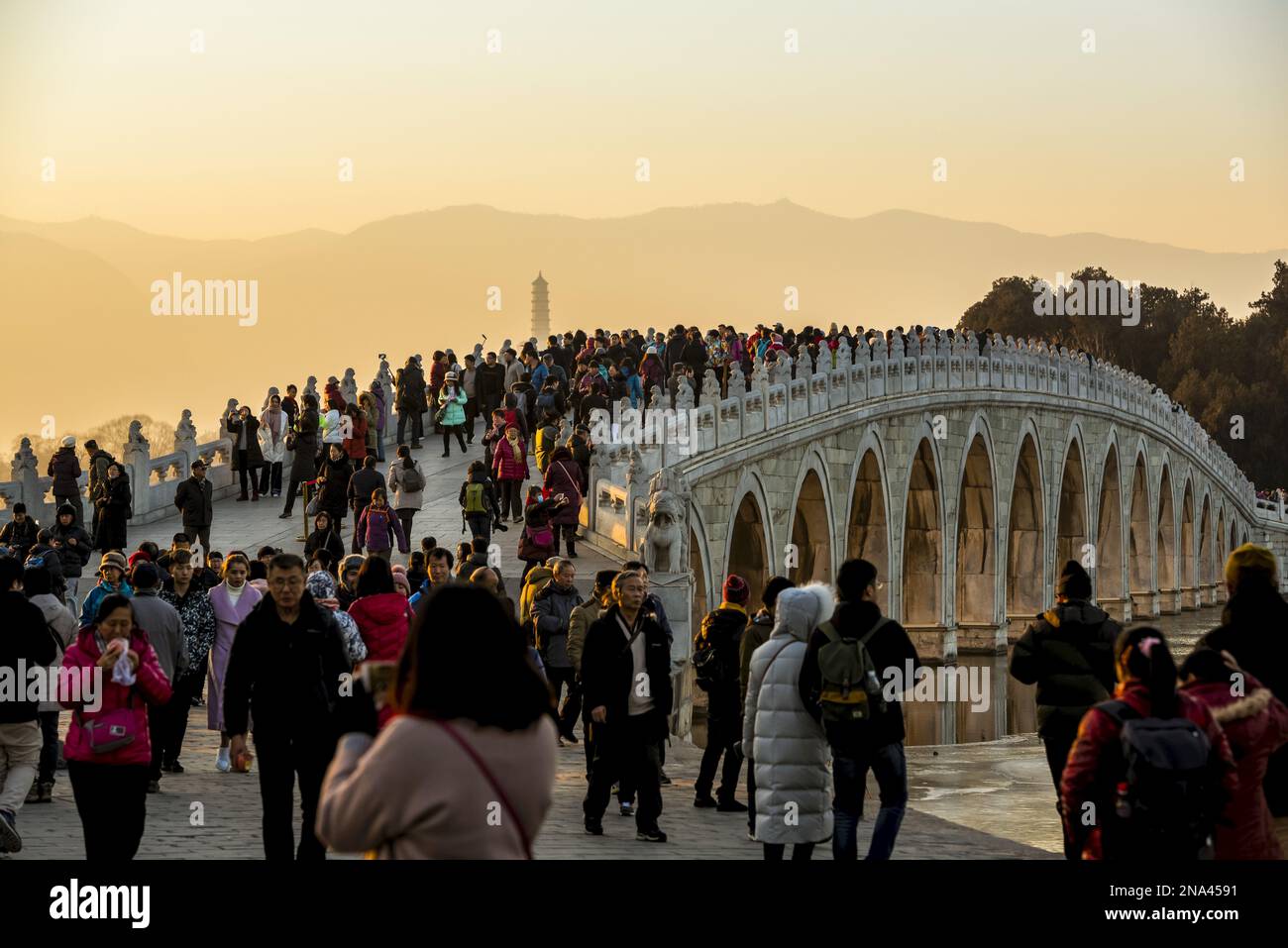 Tourists over the 17 Arch Bridge at sunset, The Summer Palace, Beijing ...