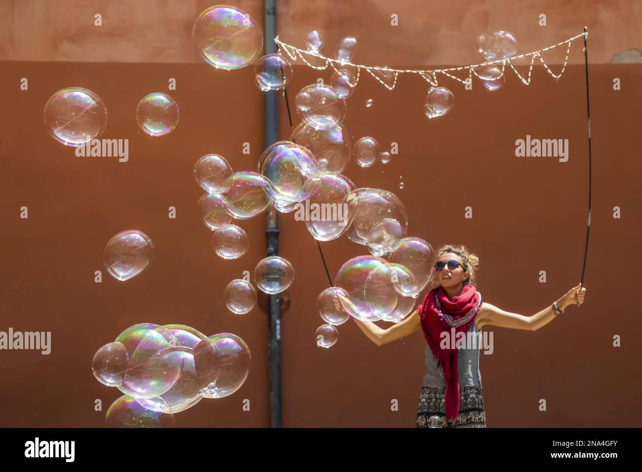 A young woman creating a performance with large bubbles; Spain Stock ...