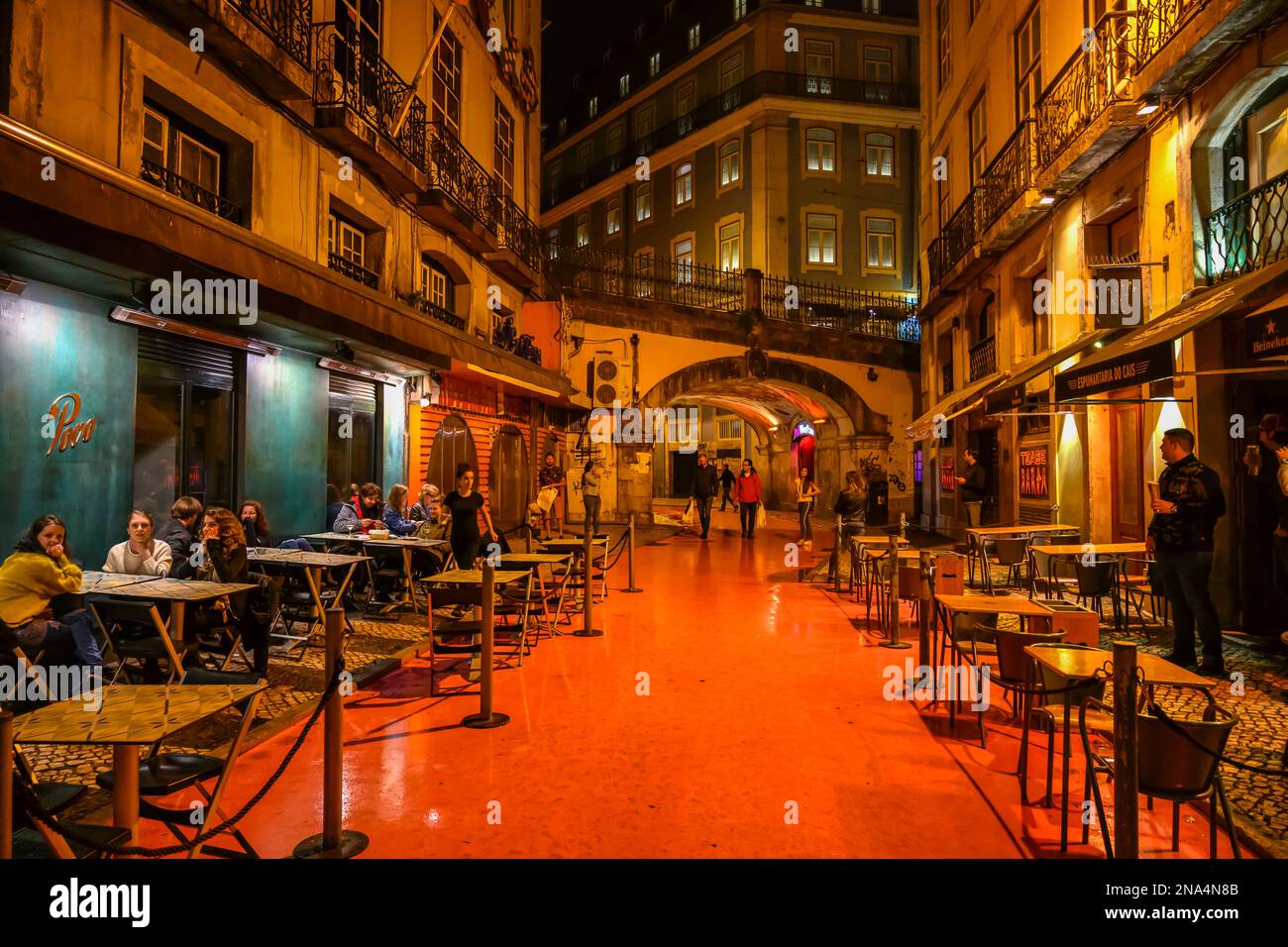 Illuminated patio seating at nighttime in between buildings with ...