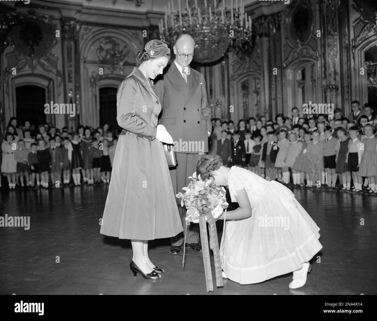 Eleven year old Pamela Brownlow presents a bouquet to Britain's Queen ...