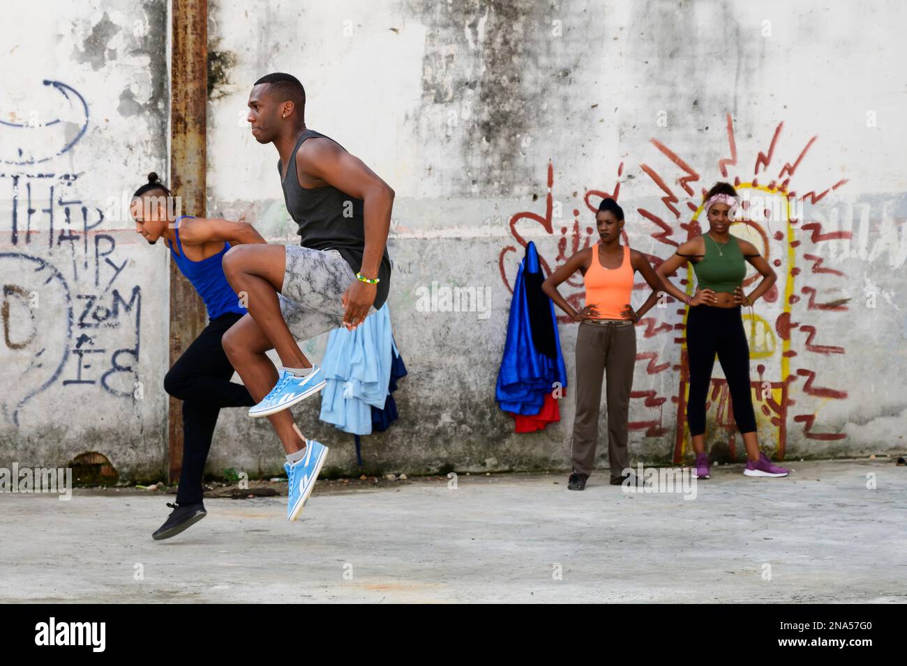Young Cuban men dancing in an old concrete building with graffiti on ...
