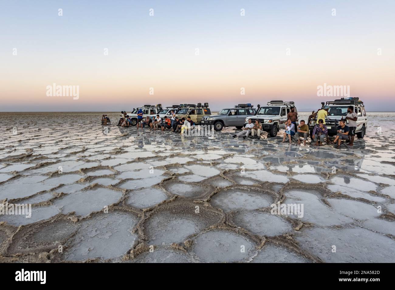Tourists in front of four-wheel drive vehicles on the salt flats of ...