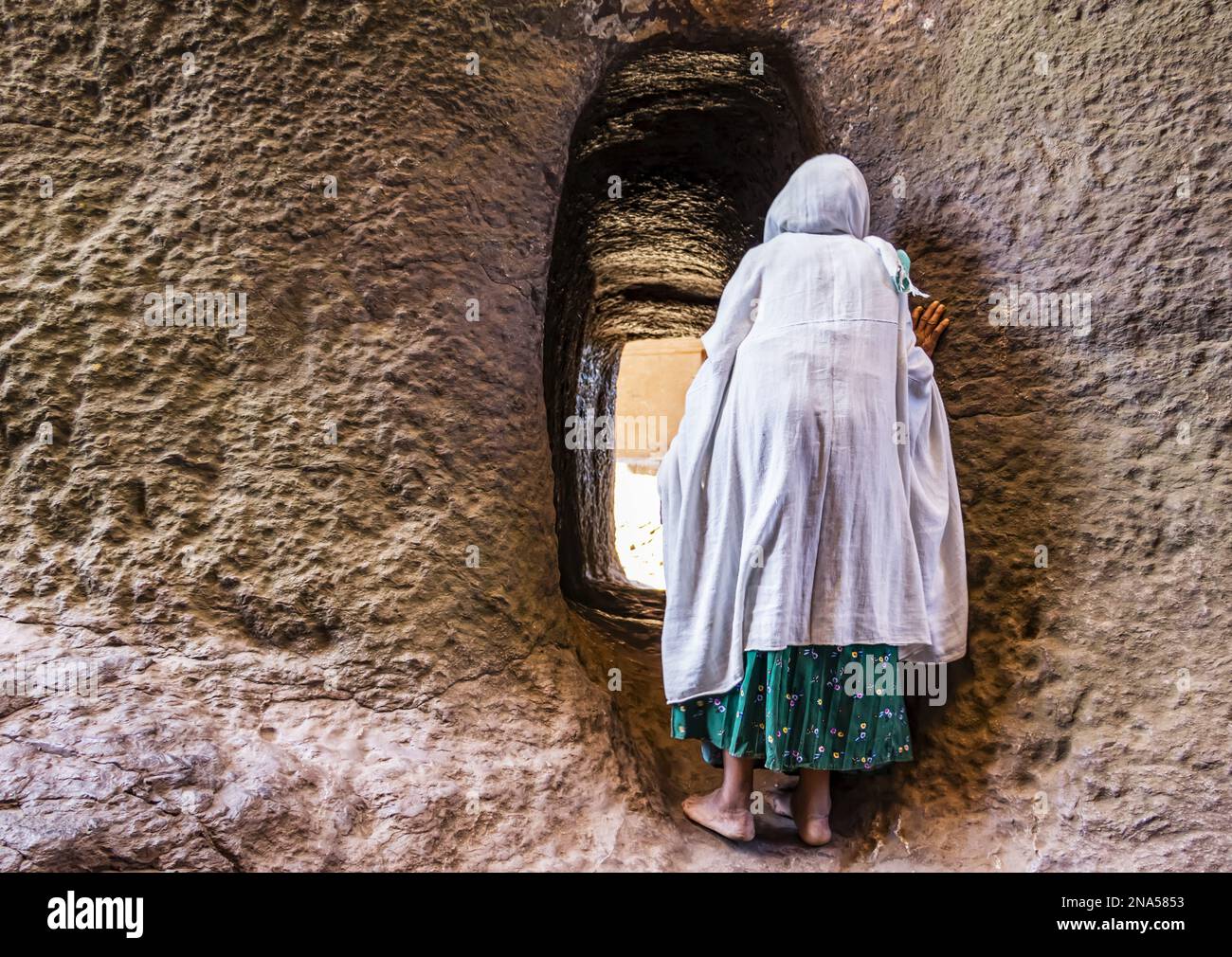 Ethiopian woman entering rock-cut tunnel between Biete Medhane Alem ...