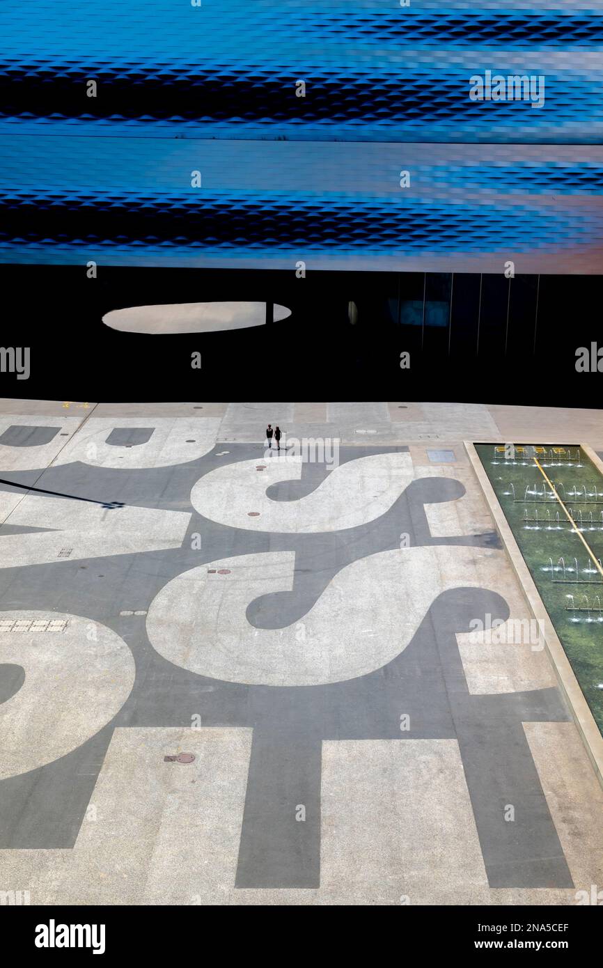Two figures stand in Messe Basel Exhibition Centre with water fountains ...