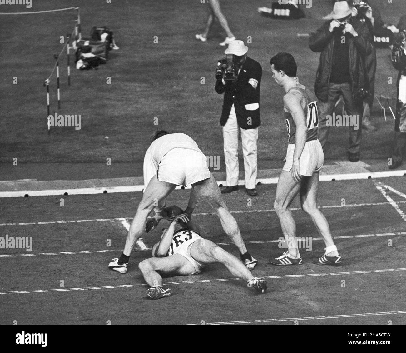 German athlete Willi Holdorf is helped by an unidentified athlete as he ...
