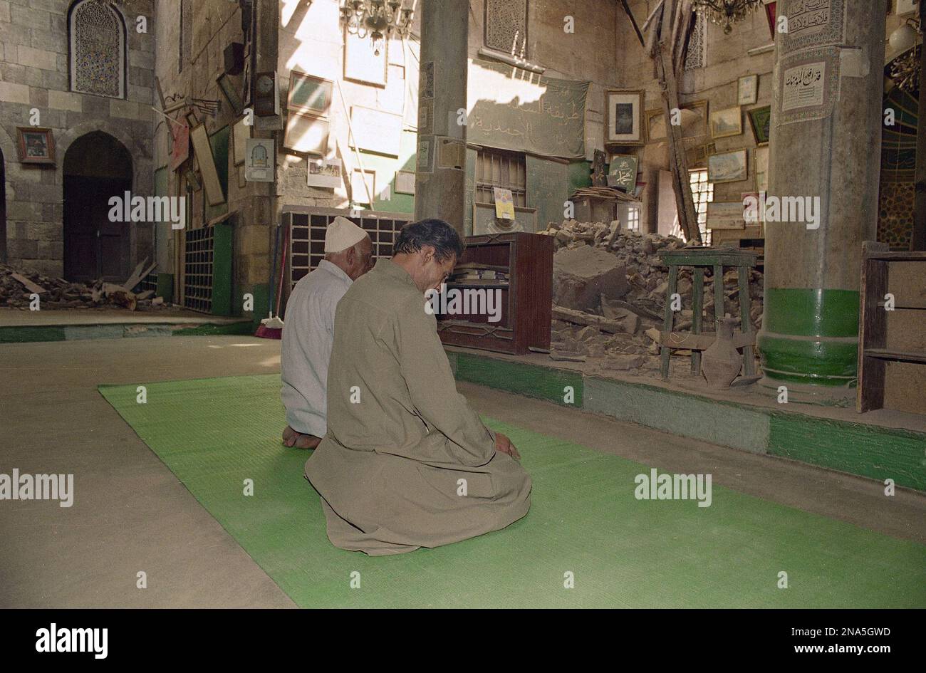 Two Muslim men kneel for Friday prayers in the damaged 500-year-old El ...
