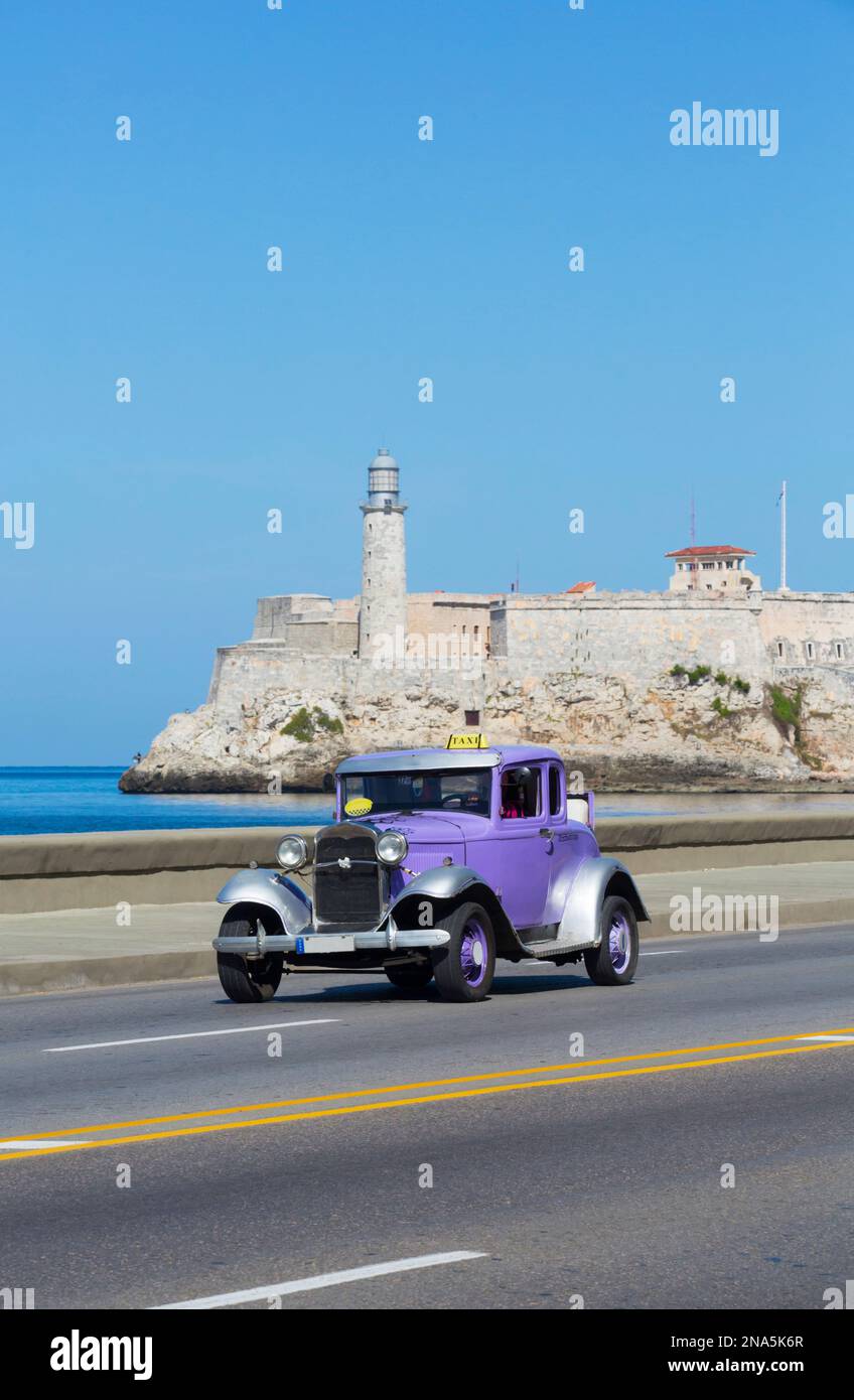 Old classic car on the Malecon, Castillo del Morro (background); Havana ...