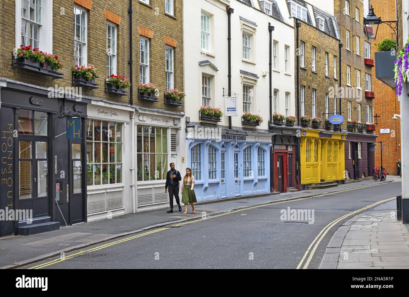 A young man and woman talk while walking down a sidewalk beside ...