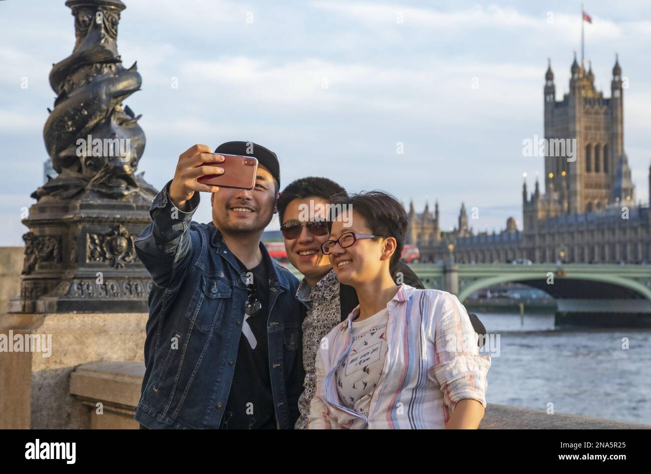 Tourists take a self-portrait along the River Thames with Victoria ...