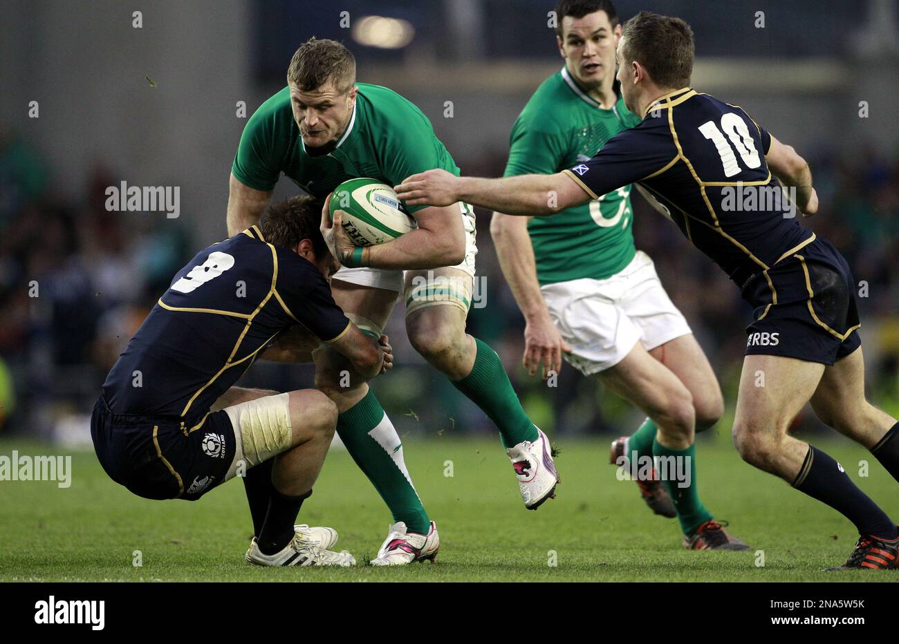 Ireland's Jamie Heaslip, center, is tackled by Scotland's Mike Blair ...