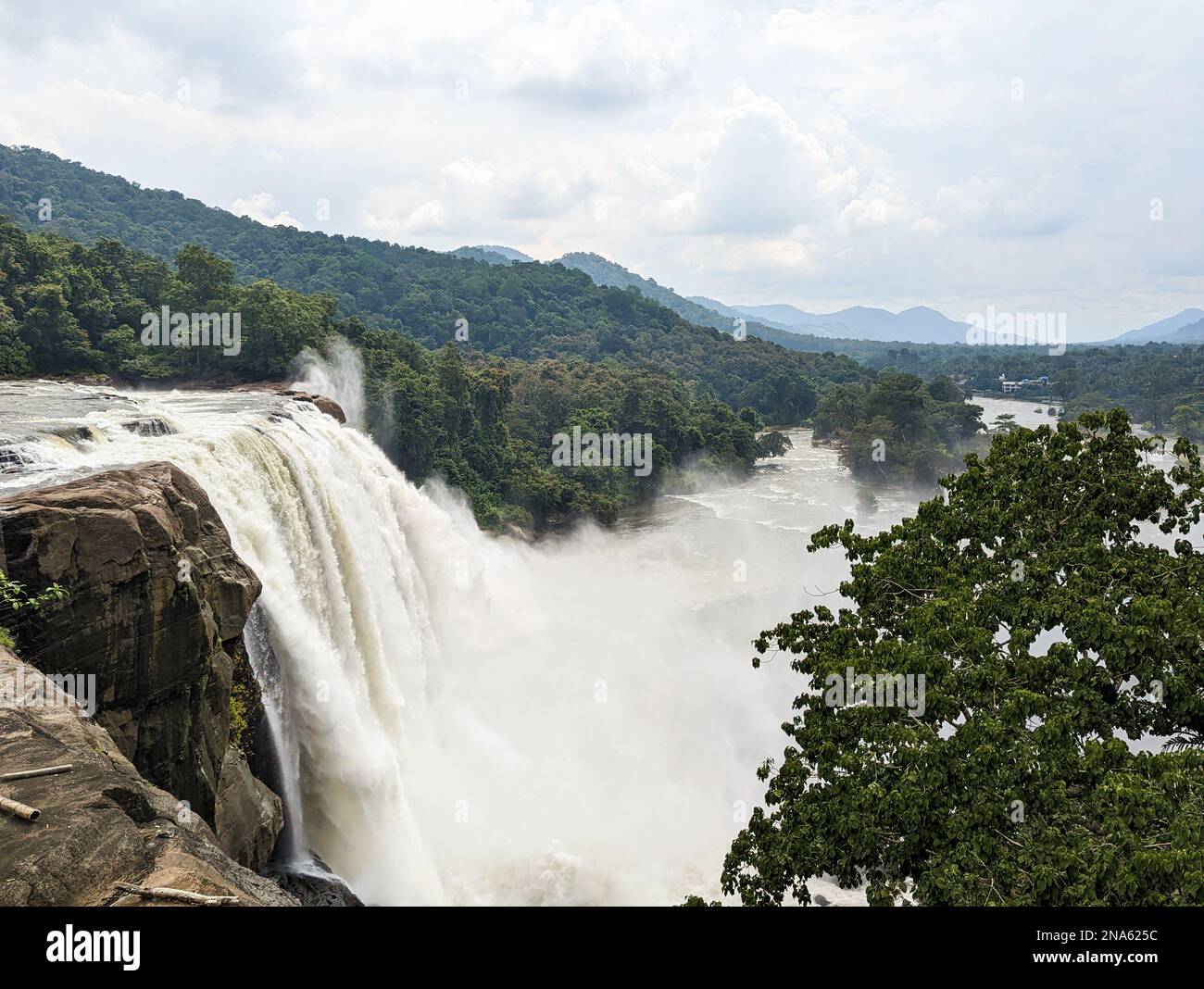 a mystical white waterfall at the center of a dark green forest ...