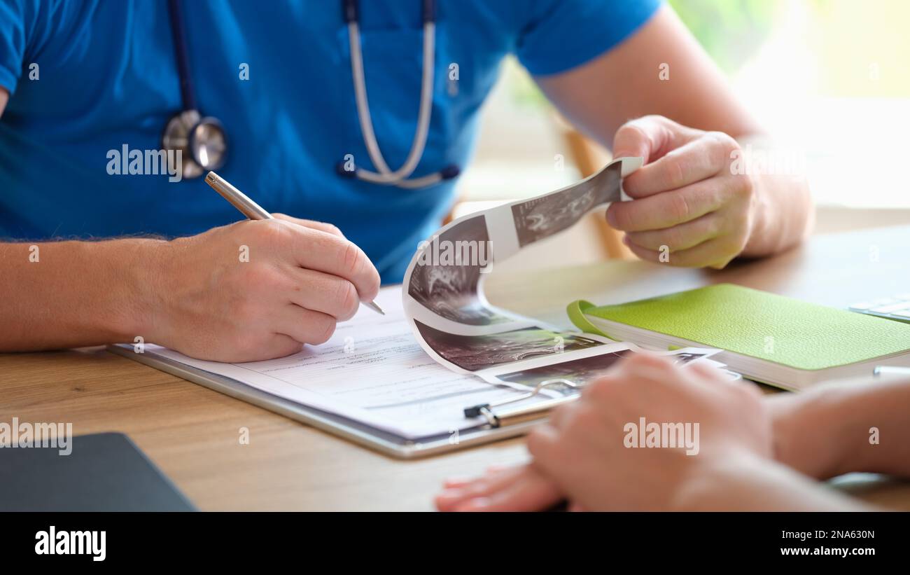 Male doctor reading patient's medical history and taking notes while ...