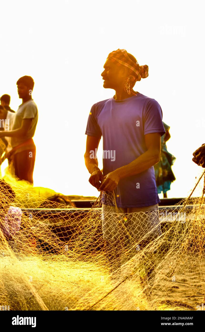 Fisherman cleaning a fishing net, Puri beach; Puri, Odisha state, India ...
