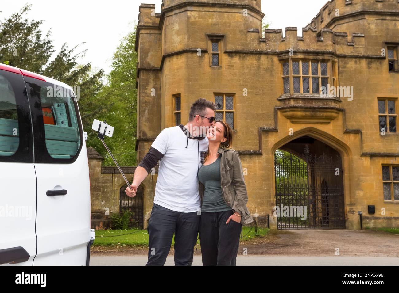 Couple traveling in camper van stop for a selfie in front of Sudeley ...