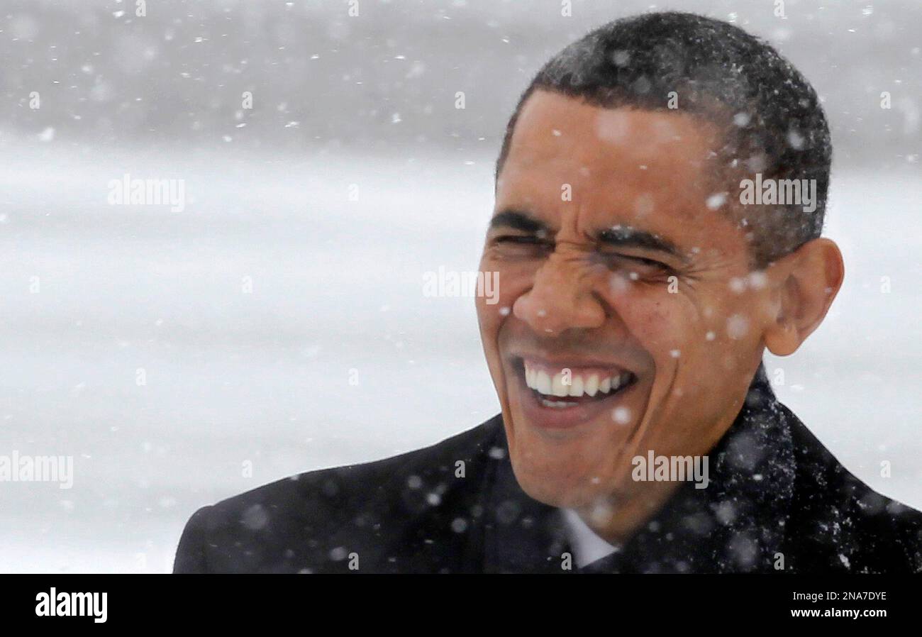 President Barack Obama smiles as he walks through a snowstorm after ...