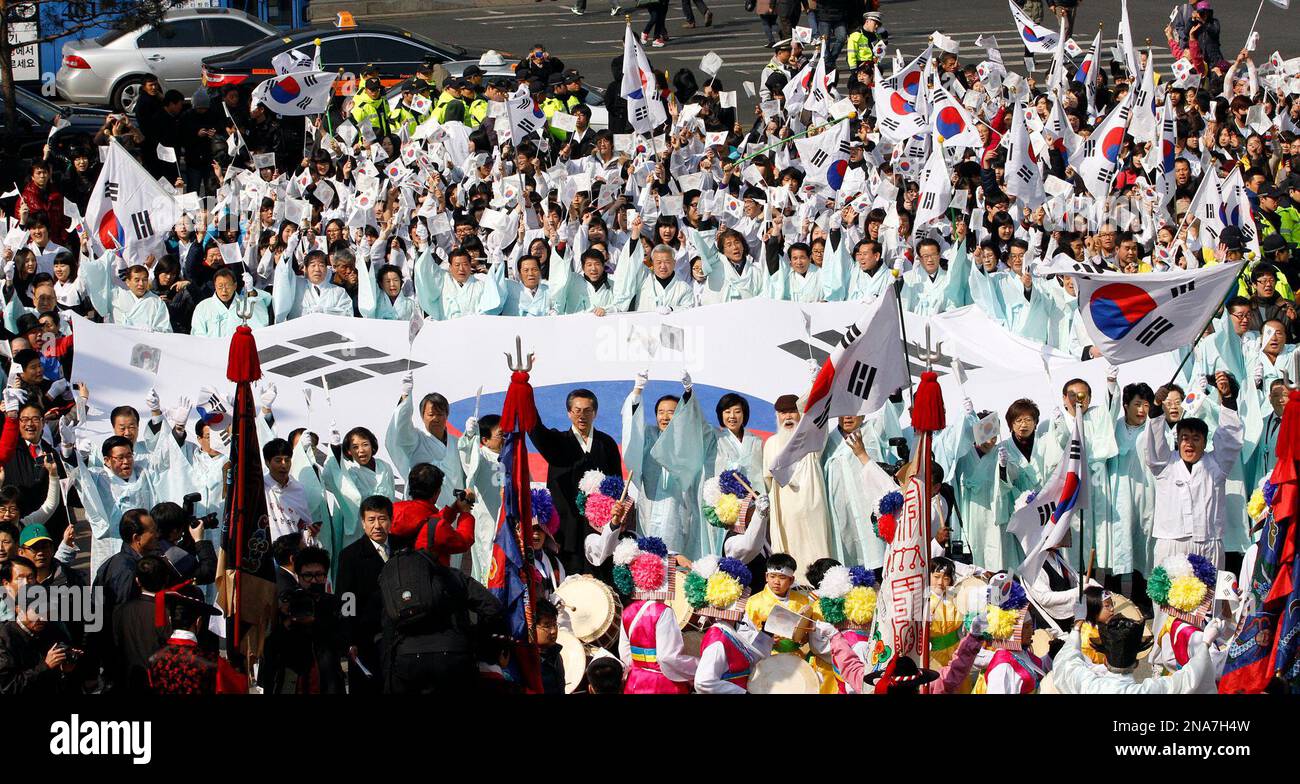 South Koreans wearing traditional Korean costumes march as they hold a ...