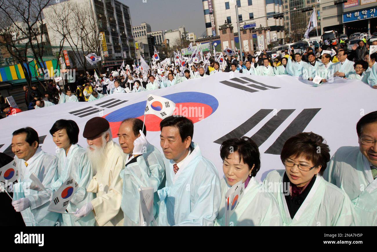 South Koreans wearing traditional Korean costumes march as they hold a ...