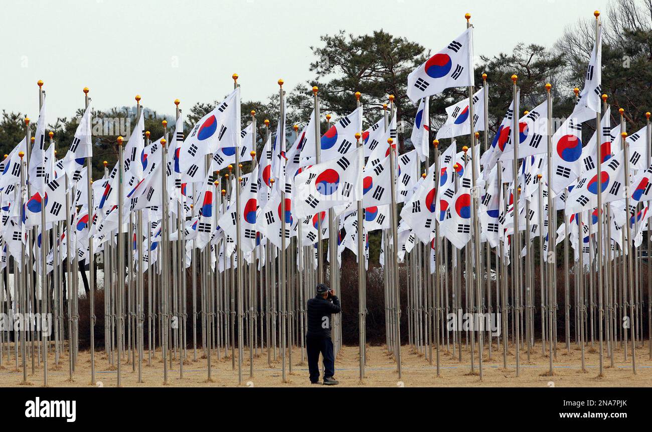 A South Korean visitor takes pictures near the national flags on ...