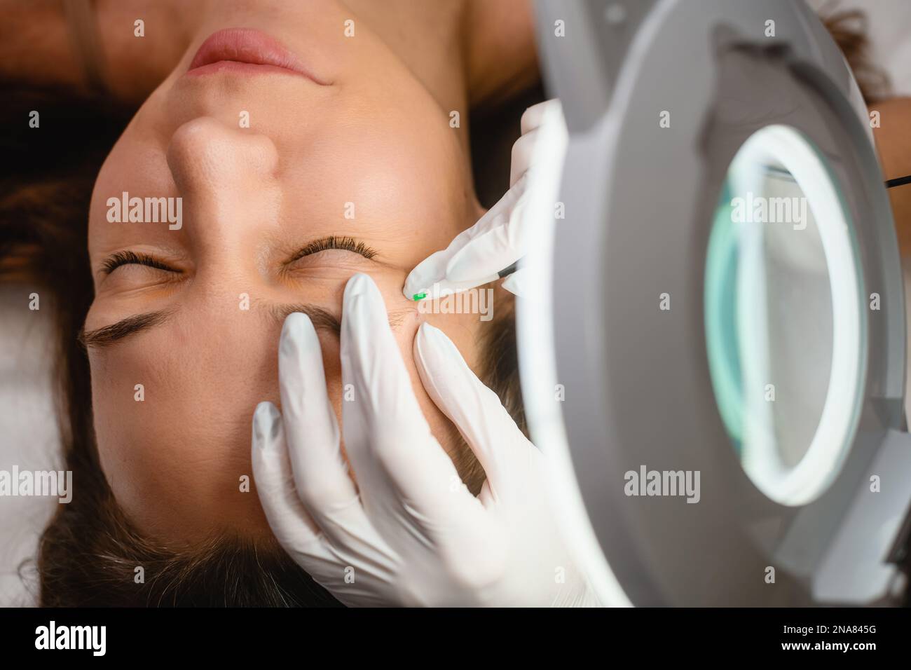 Female face under light in cosmetology clinic, relaxed woman laying ...