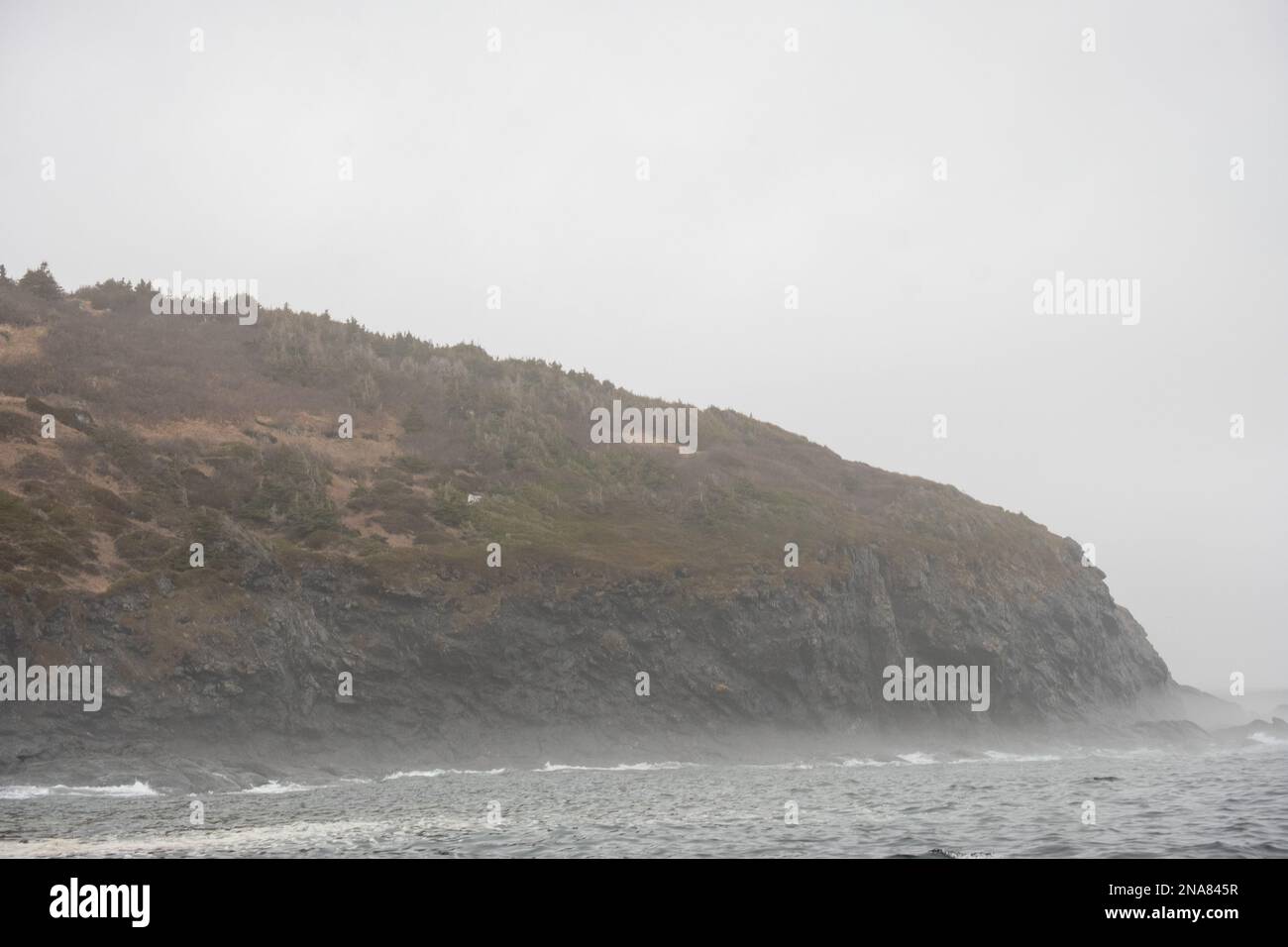 A scenic view of sea waves crashing against rocky cliffs on a stormy ...