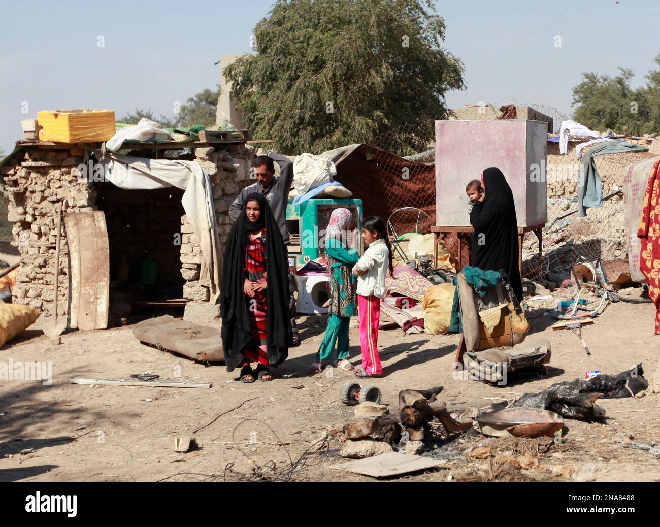 A homeless family stands at a compound for displaced people in western ...