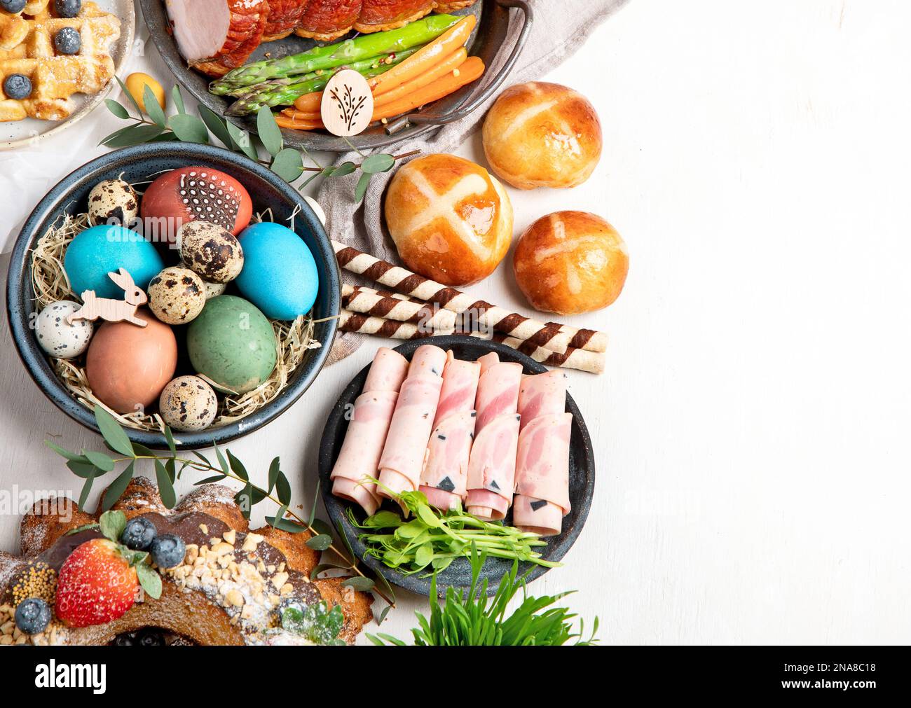Traditional Easter dinner or brunch with ham, colored eggs, hot cross ...