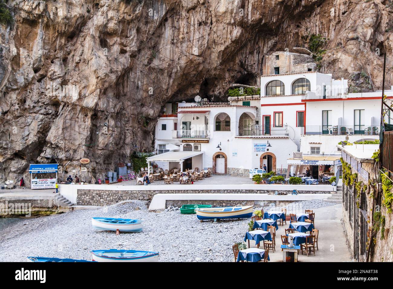 Outdoor restaurant in Praiano with seating on a patio and rowboats on ...