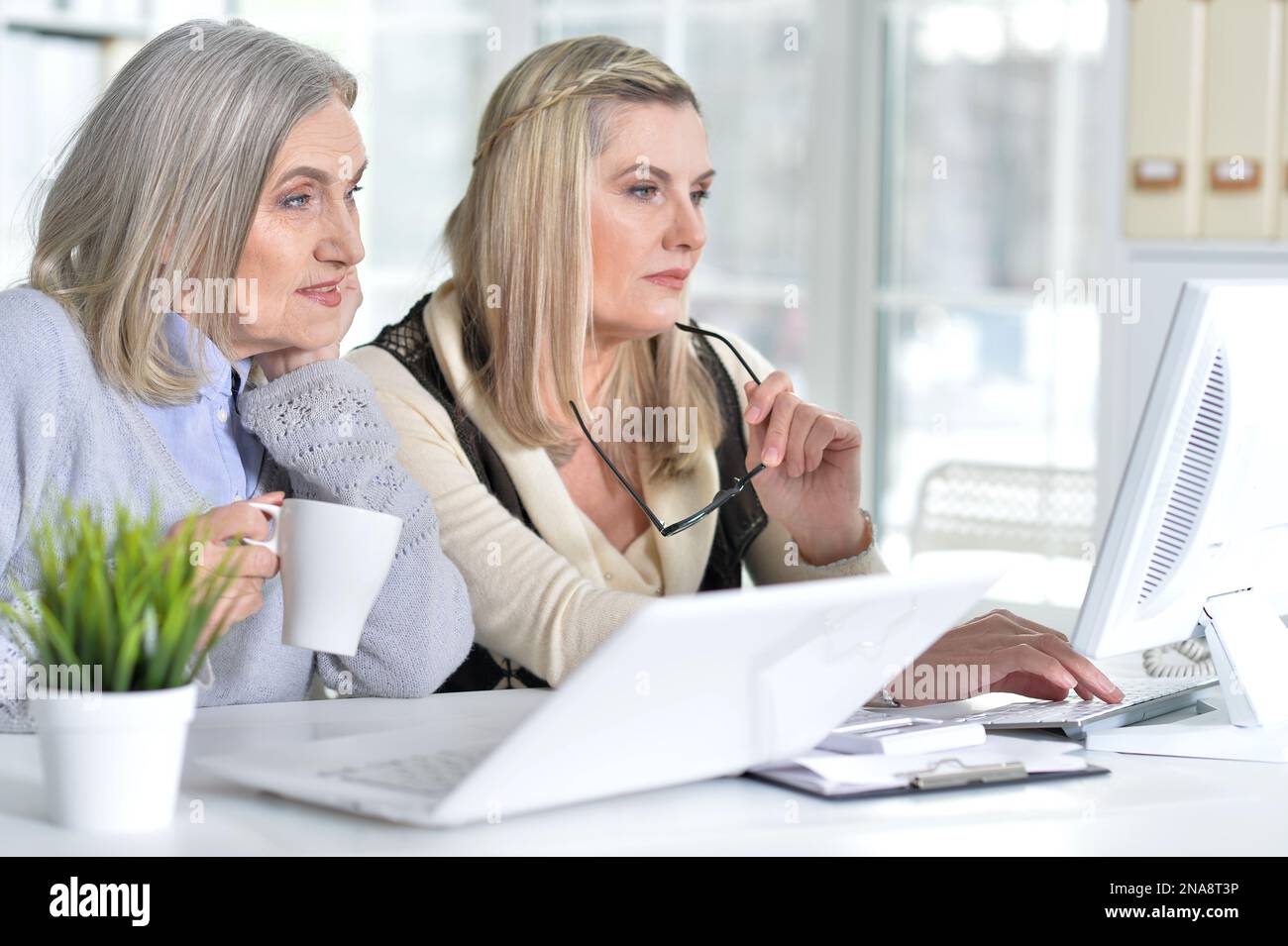 two excited mature women working in office Stock Photo - Alamy