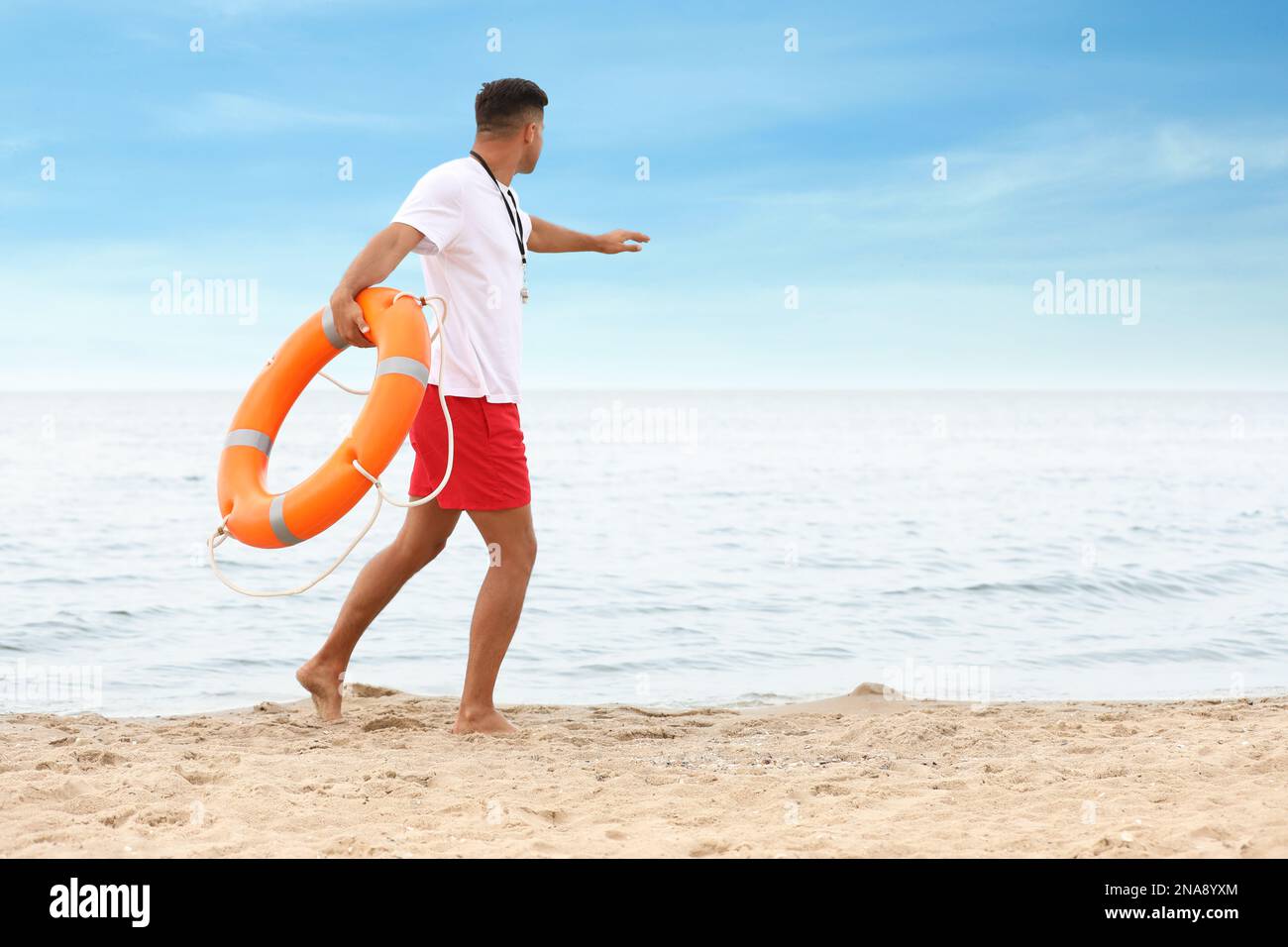 Handsome male lifeguard with life buoy at sandy beach Stock Photo - Alamy