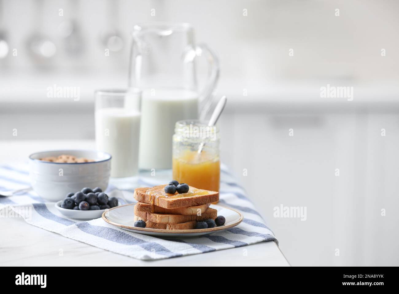 Toasted bread with jam and blueberries on white marble table in kitchen ...