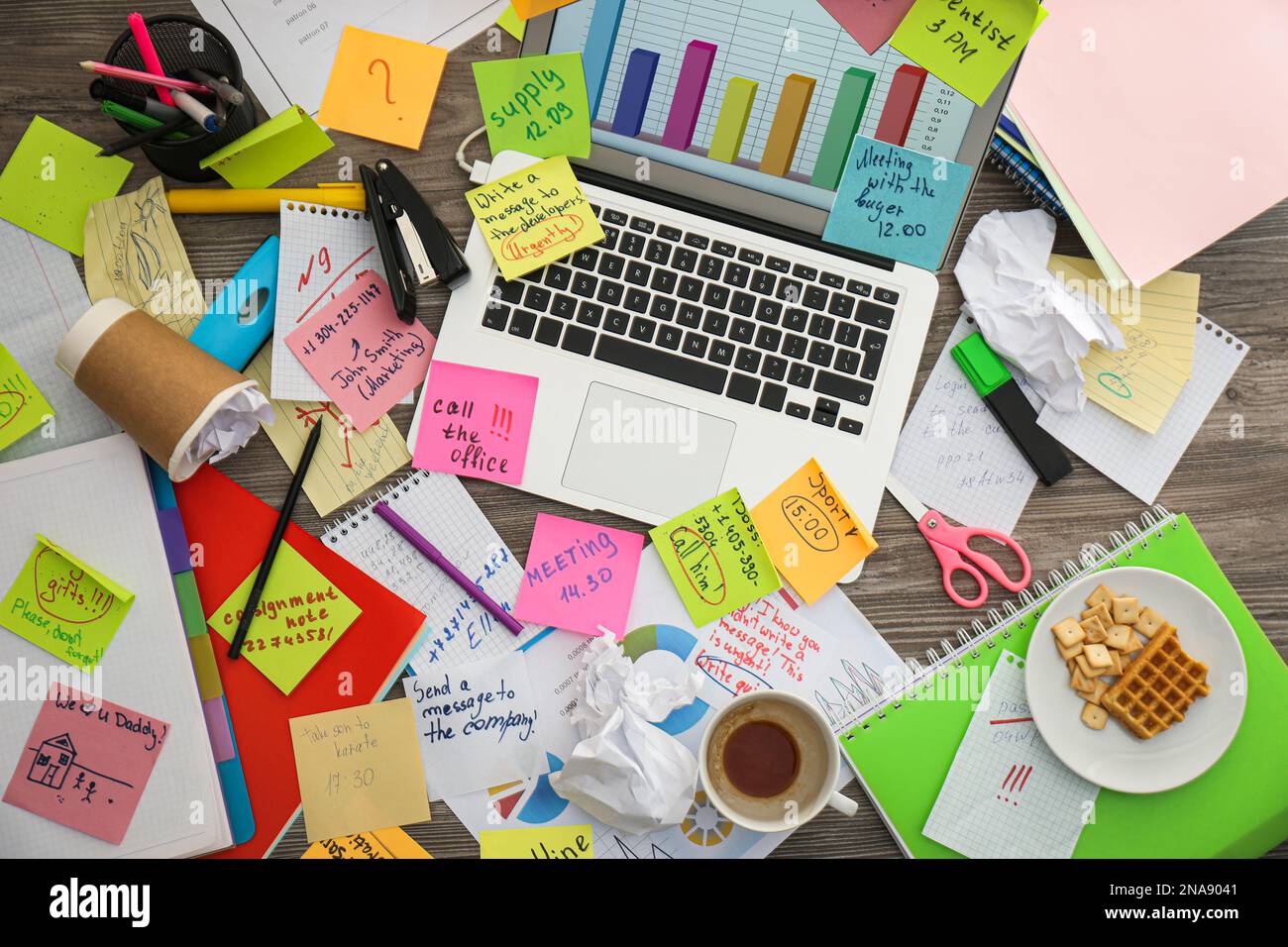 Laptop, notes and office stationery in mess on desk, top view ...