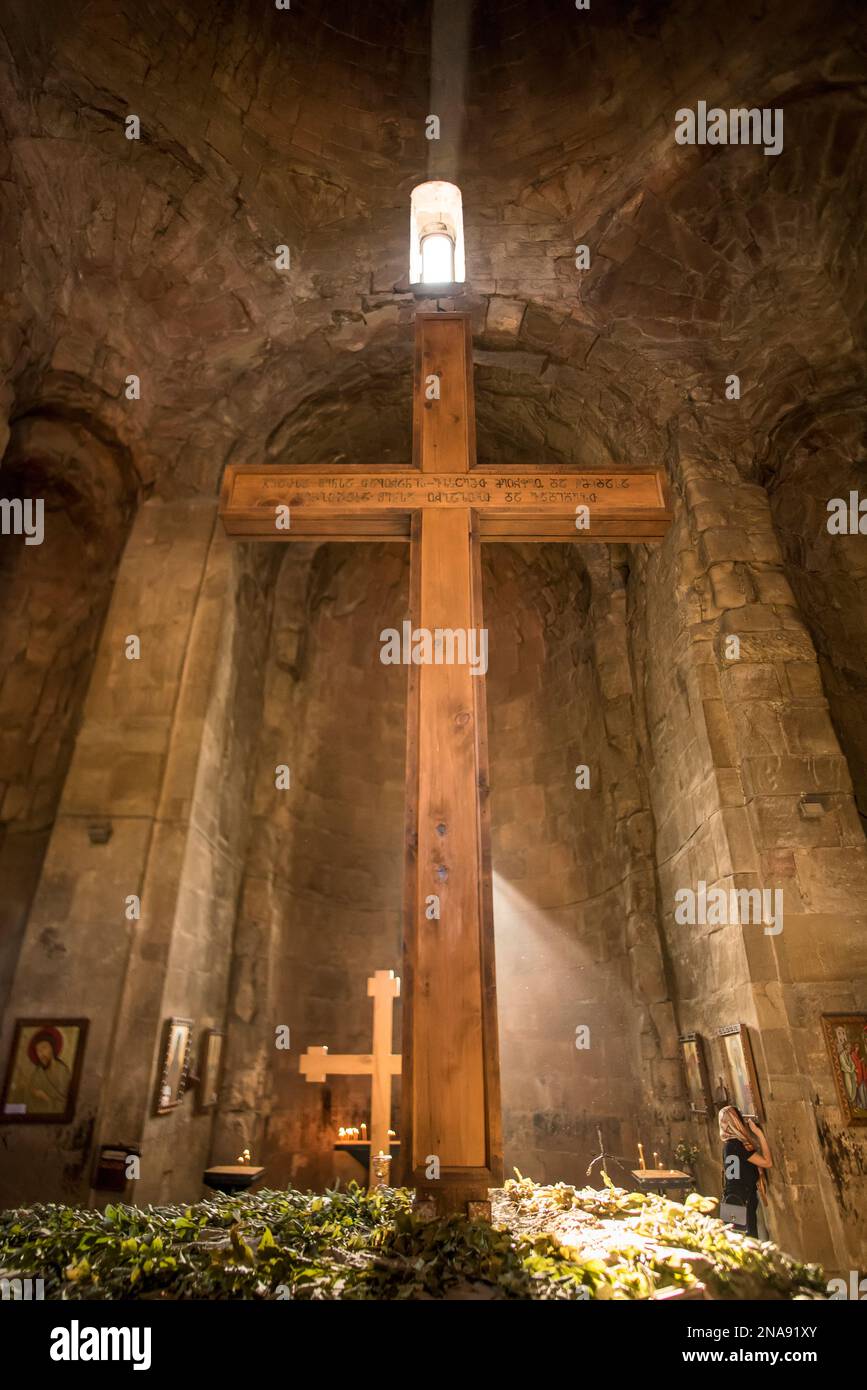 Sunlight streams into Jvari Monastery over a cross, as a woman prays in ...