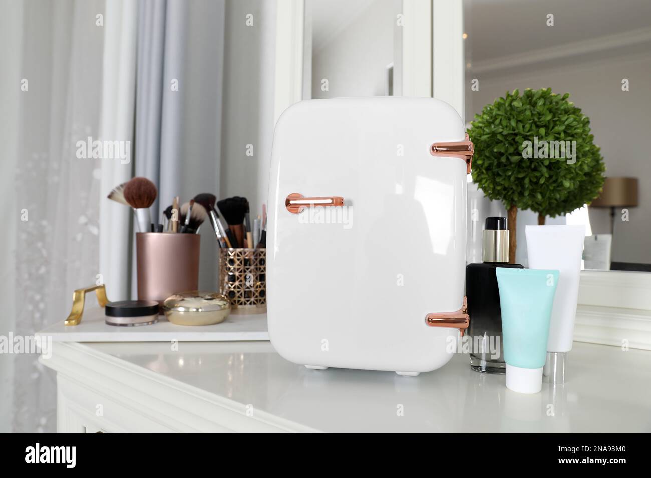 Mini fridge for cosmetic products on white vanity table Stock Photo - Alamy