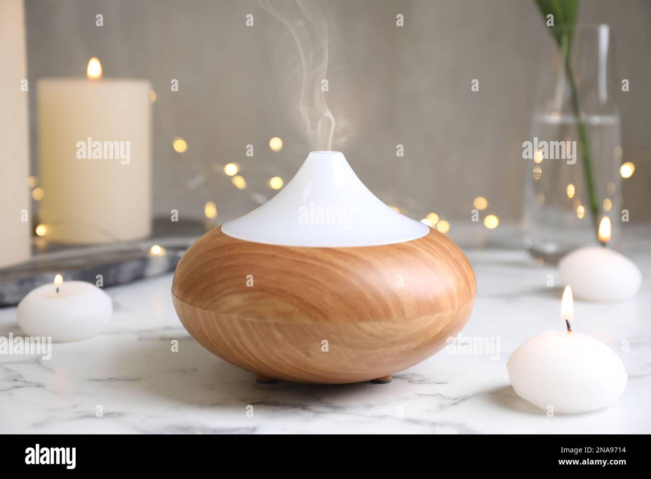 Aroma oil diffuser and burning candles on white marble table Stock Photo - Alamy
