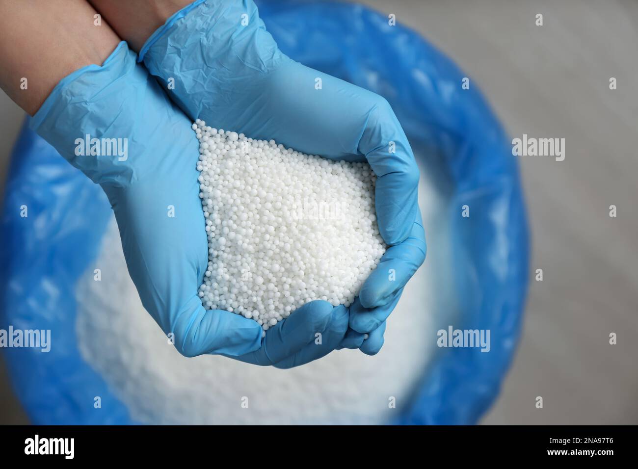 Person in gloves holding pile of ammonium nitrate pellets over bag, top ...