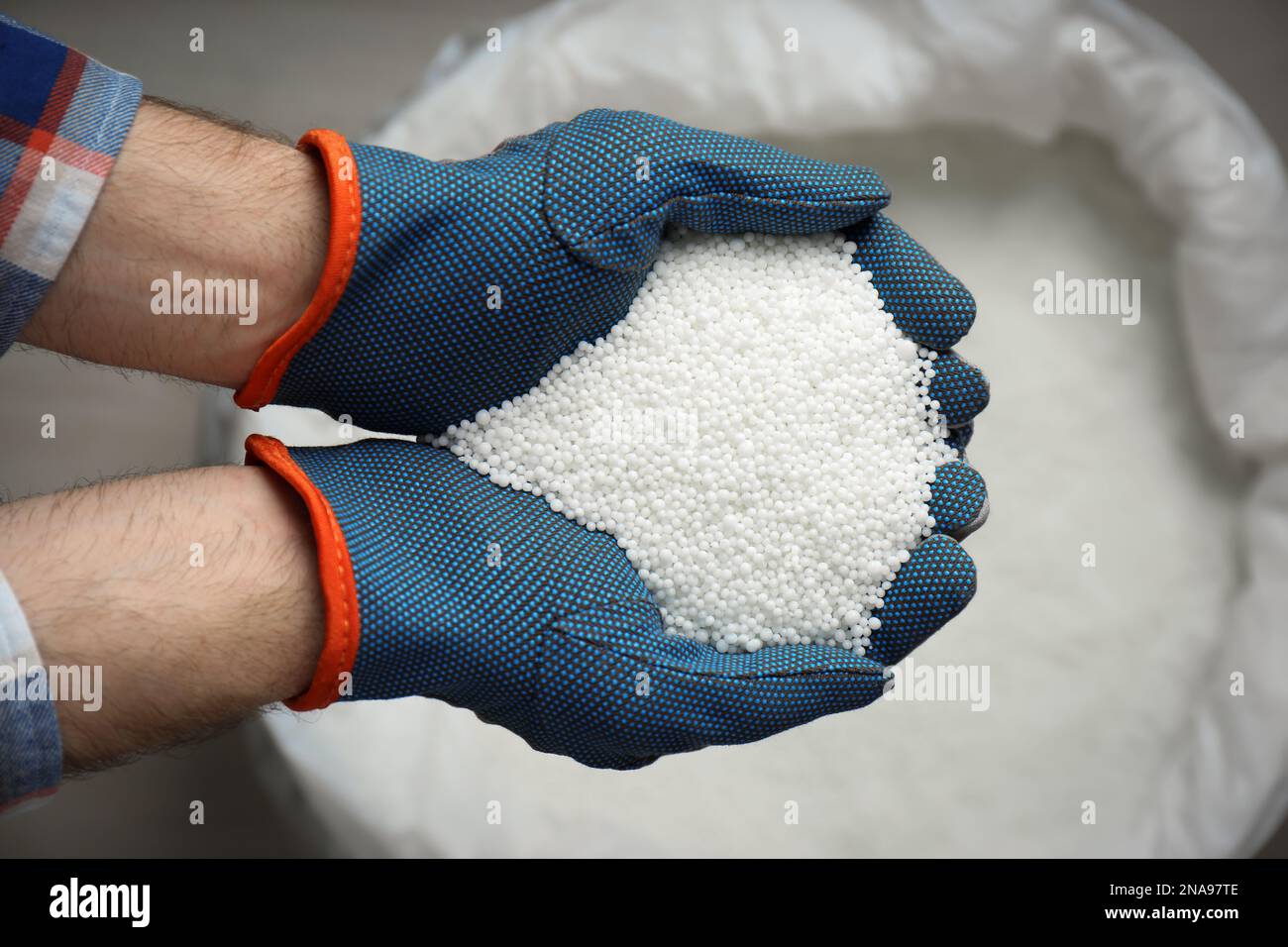 Farmer holding pile of ammonium nitrate pellets over bag, top view ...
